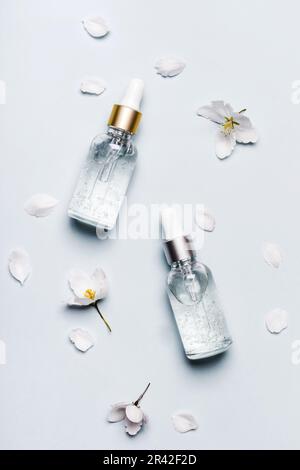 Cosmetic skin care products with flowers and wood on blue background ...