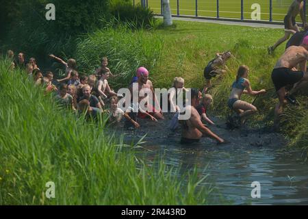 Group of people in a muddy ditch having fun during survival weekend ...