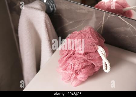 Pink shower puff on washbasin in bathroom, closeup. Space for text ...