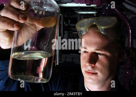 US Navy Airman inspects a sample of JP5 jet fuel from an F-A-18 Hornet ...