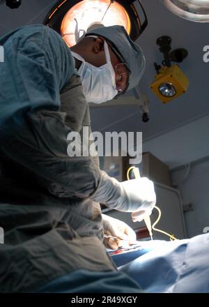 US Navy Cmdr. ship's surgeon, and Hospital Corpsman 1st Class perform a ...