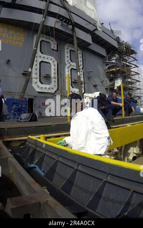 An Aviation Ordnanceman paints boundary markings on the flight deck ...