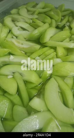 Vibrant yellow melon slices arranged on a white ceramic plate with a ...