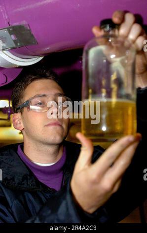 US Navy Airman inspects a sample of JP5 jet fuel from an F-A-18 Hornet ...
