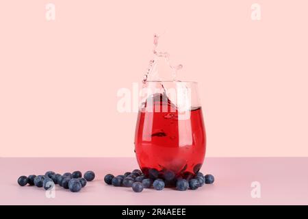 Glass of tasty blueberry cider with splashes, ice cube and berries ...