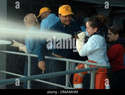 US Navy Damage Control Training Team members help a Sailor don ...