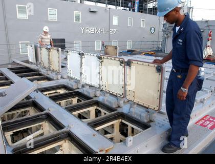Gunner's Mate 2nd Class inspects missile cell hatches on two Vertical ...
