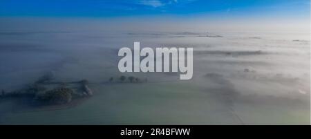 An aerial view of a small town shrouded in a misty fog, with white ...