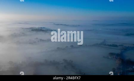 An aerial view of a small town shrouded in a misty fog, with white ...