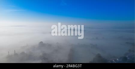 An aerial view of a small town shrouded in a misty fog, with white ...