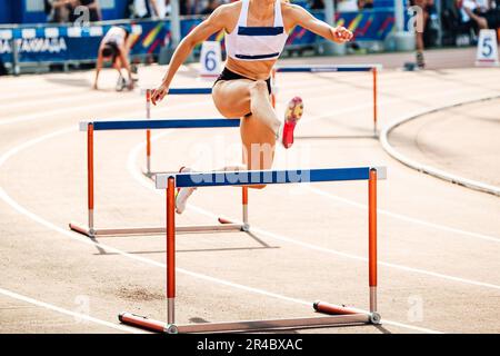 female athlete running 400 meters hurdles race in summer athletics ...