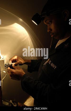 US Navy Electrician's Mate 2nd Class left, and Airman replace a light ...