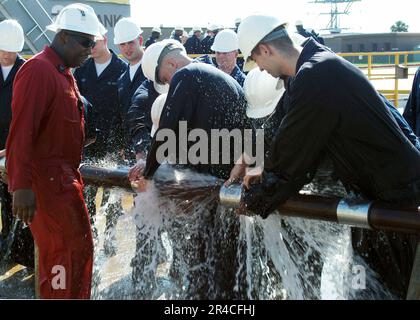 US Navy Damage Controlman assists with the firefighting gear of ...