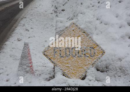 Snow-covered flooded sign with cone next to highway Stock Photo - Alamy