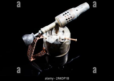 old and vintage blow torch isolated on black background with rust and ...