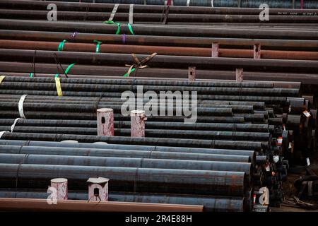 Steel pipes and tubes outdoor warehouse. Wet metal in rainy day. View ...