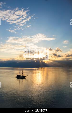 A single ship silhouetted against a beautiful sunset sky on the open ...