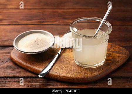 Glass of agar-agar jelly and powder on wooden table. Space for text ...
