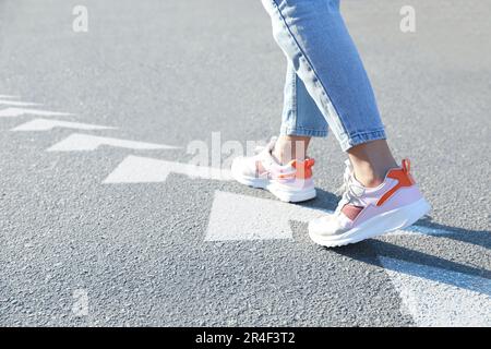 Planning future. Woman walking on drawn marks on road, closeup. White ...