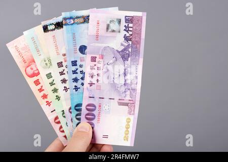 Taiwan money in the hand on a gray background Stock Photo - Alamy