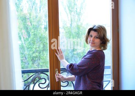 Woman opens or closes window to the balcony Stock Photo - Alamy