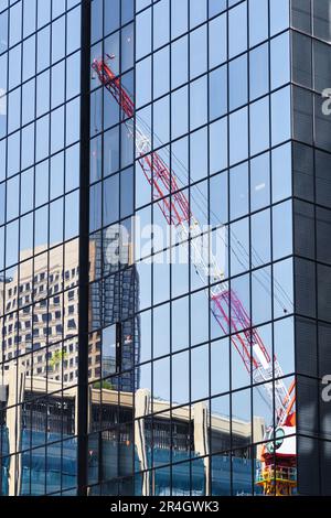 picture of a construction crane that reflects in windows of modern high ...