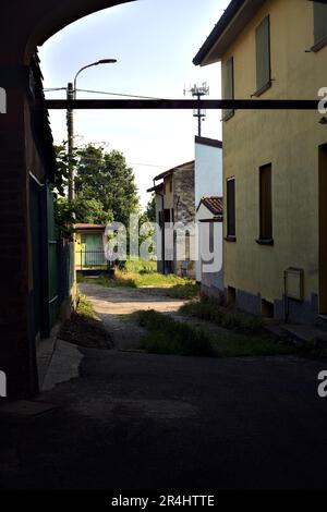 Covered alley between buildings that leads to a path next to a field on ...