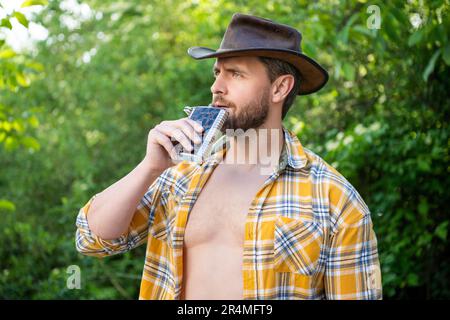 masculine cowboy drink from flask wear hat. photo of masculine cowboy ...