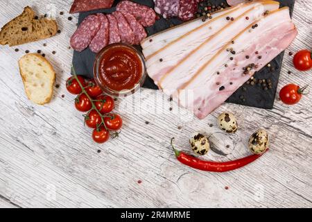 Antipasti different types of sausages and lard on a graphite board .Top ...