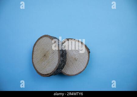 Small round logs, photographed from above, placed on the edge of a blue ...