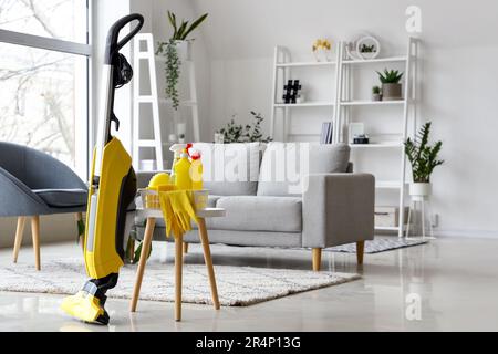 Table with cleaning supplies and hoover in living room Stock Photo - Alamy