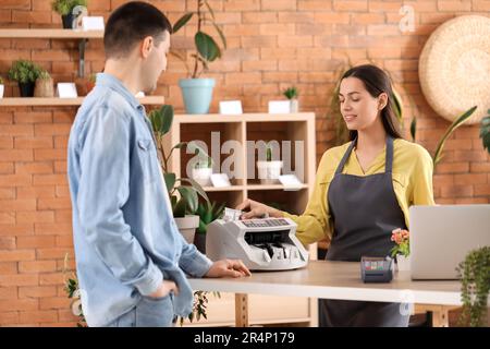 Female cashier using cash counting machine in flower shop Stock Photo ...