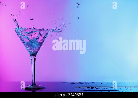 Glass of martini and splashes in neon lights on dark background, bokeh ...