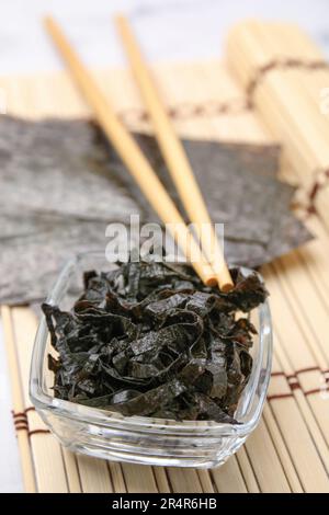 Bamboo mat, natural nori sheets, chopsticks and bowl of rice isolated ...
