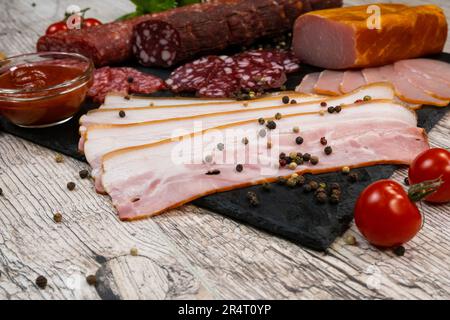 Antipasti different types of sausages and lard on a graphite board .Top ...
