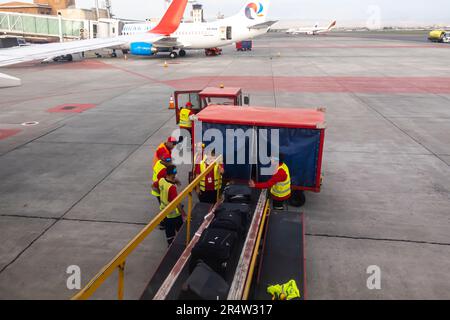 Aircraft ramp loader loading baggage to conveyor belt on airport apron ...