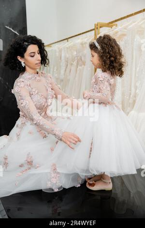 charming middle eastern bride with brunette hair standing in white ...