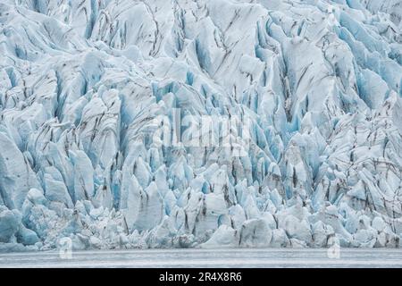 Stunning view of the silt streaked, jagged blue ice shapes of a glacier ...
