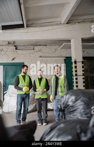 Cheerful multiethnic sorters in high visibility vests and gloves ...