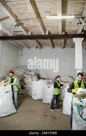Multiethnic workers in high visibility vests and gloves separating ...