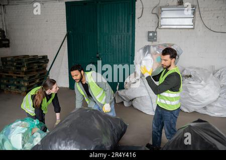 Multiethnic workers in high visibility vests and gloves separating ...