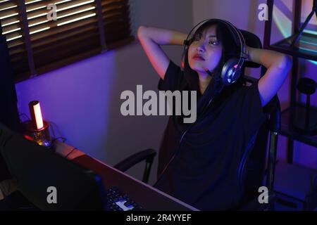 Female cyber hacker gamer holds hands behind head to resting after ...