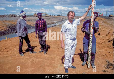 Mozambique, Maputo; A man is surveying land while construction workers ...