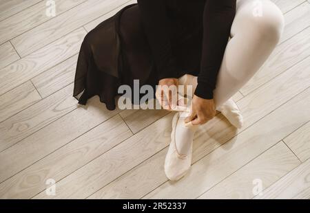 Anonymous dancer in black dress sitting on the floor and wearing ballet ...