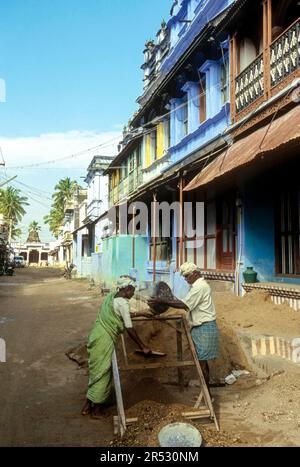 Labourer in the process of sand shieving on the street of ...