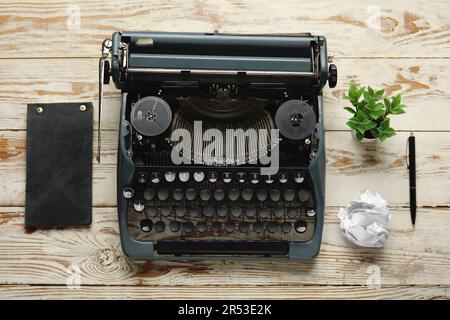 Vintage typewriter with crumpled paper and houseplant on brown wooden ...