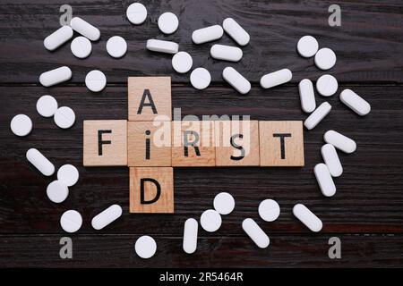 Words First Aid made of wooden cubes and cardboard heart on grey ...
