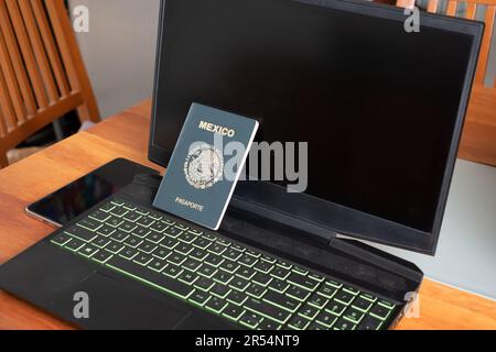 Mexican passport on black laptop computer. Out of focus background of a ...
