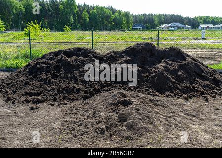 A heap of pure black earth lying in the yard next to the fence, visible ...