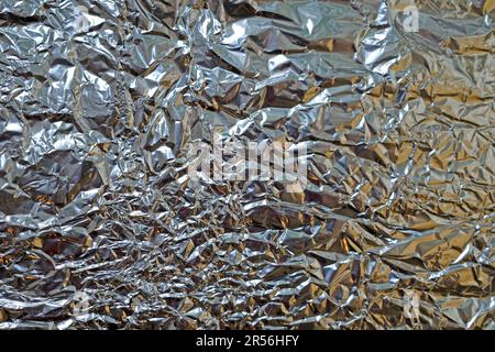 Crumpled aluminum foil reflecting light, creating abstract silver ...